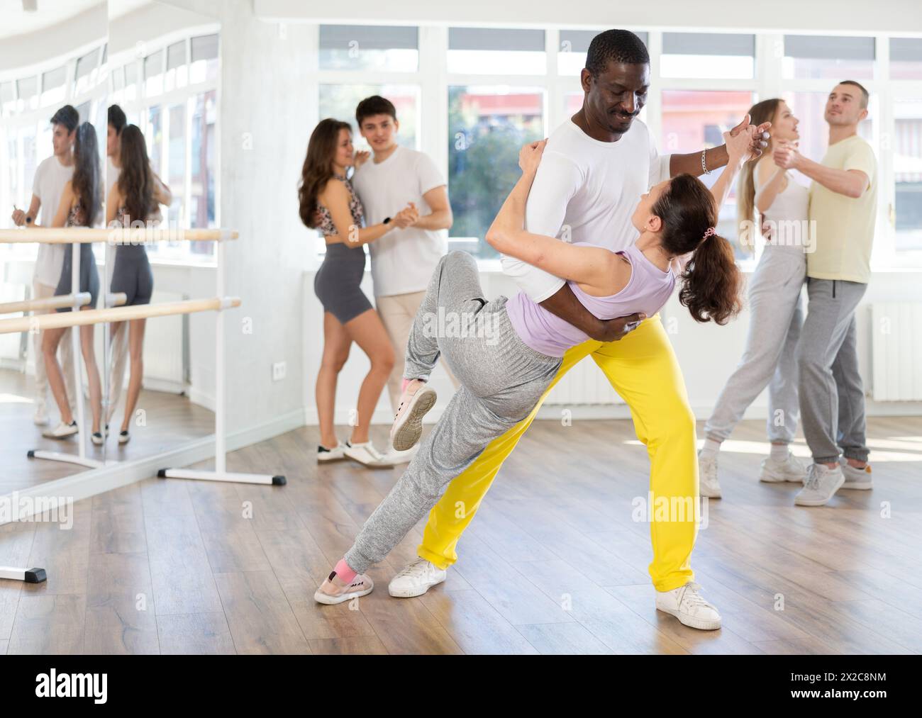 Smiling young woman wearing sportswear dancing in couple samba dance ...