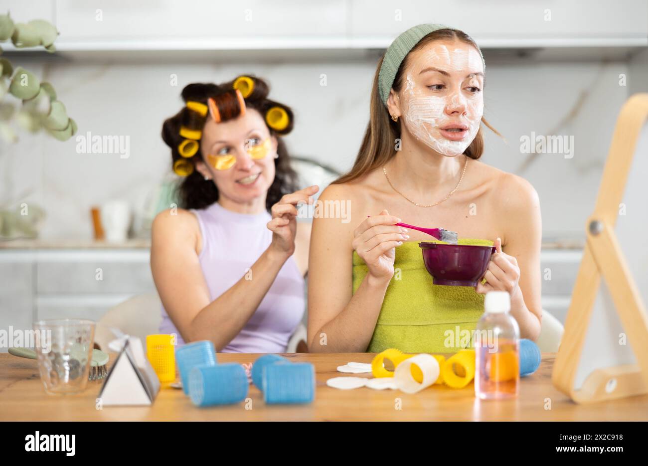 Woman applying facial mask during home spa day with bestie Stock Photo ...