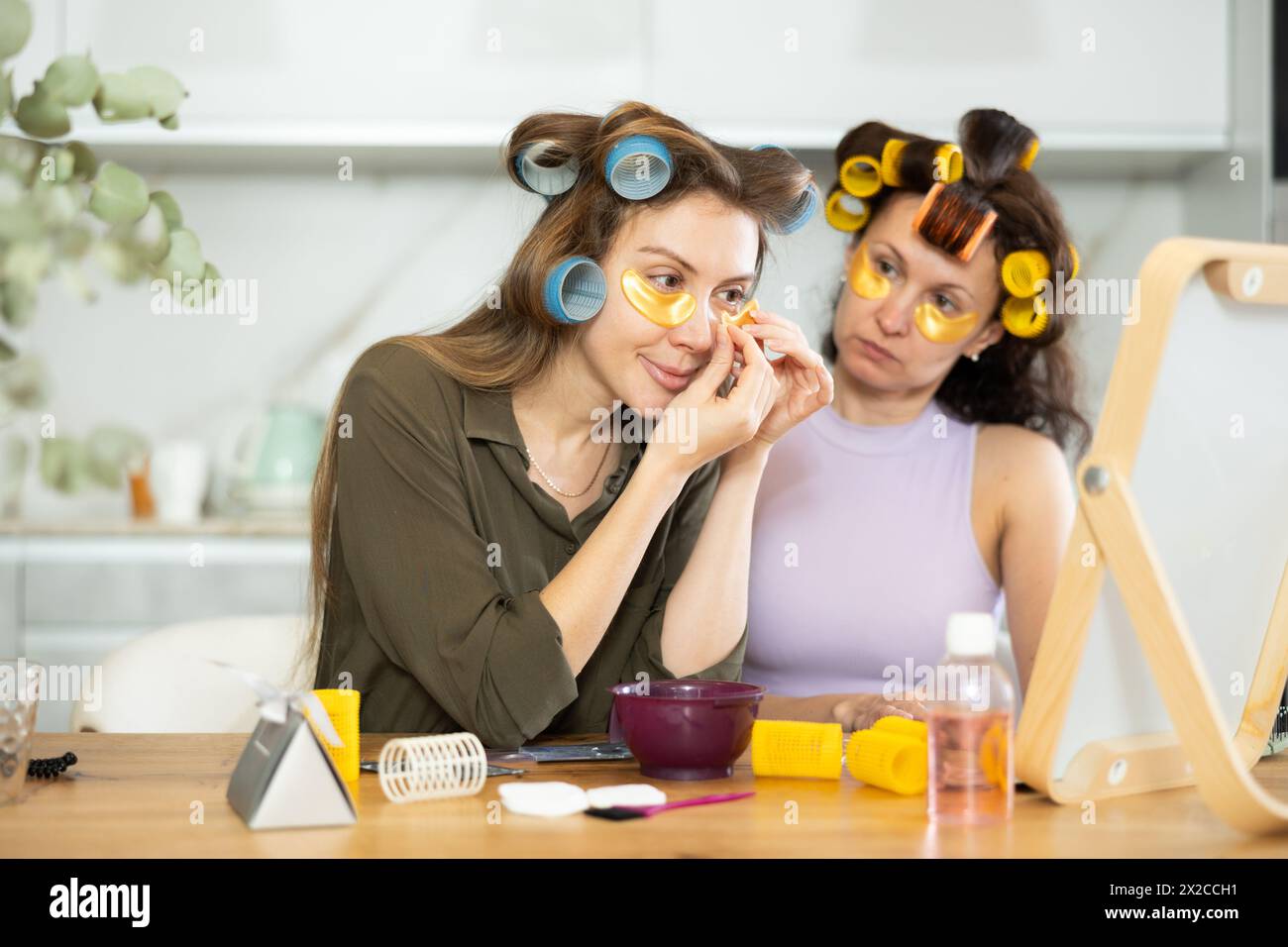 Female friends in curlers using under-eye patches during self-care ...