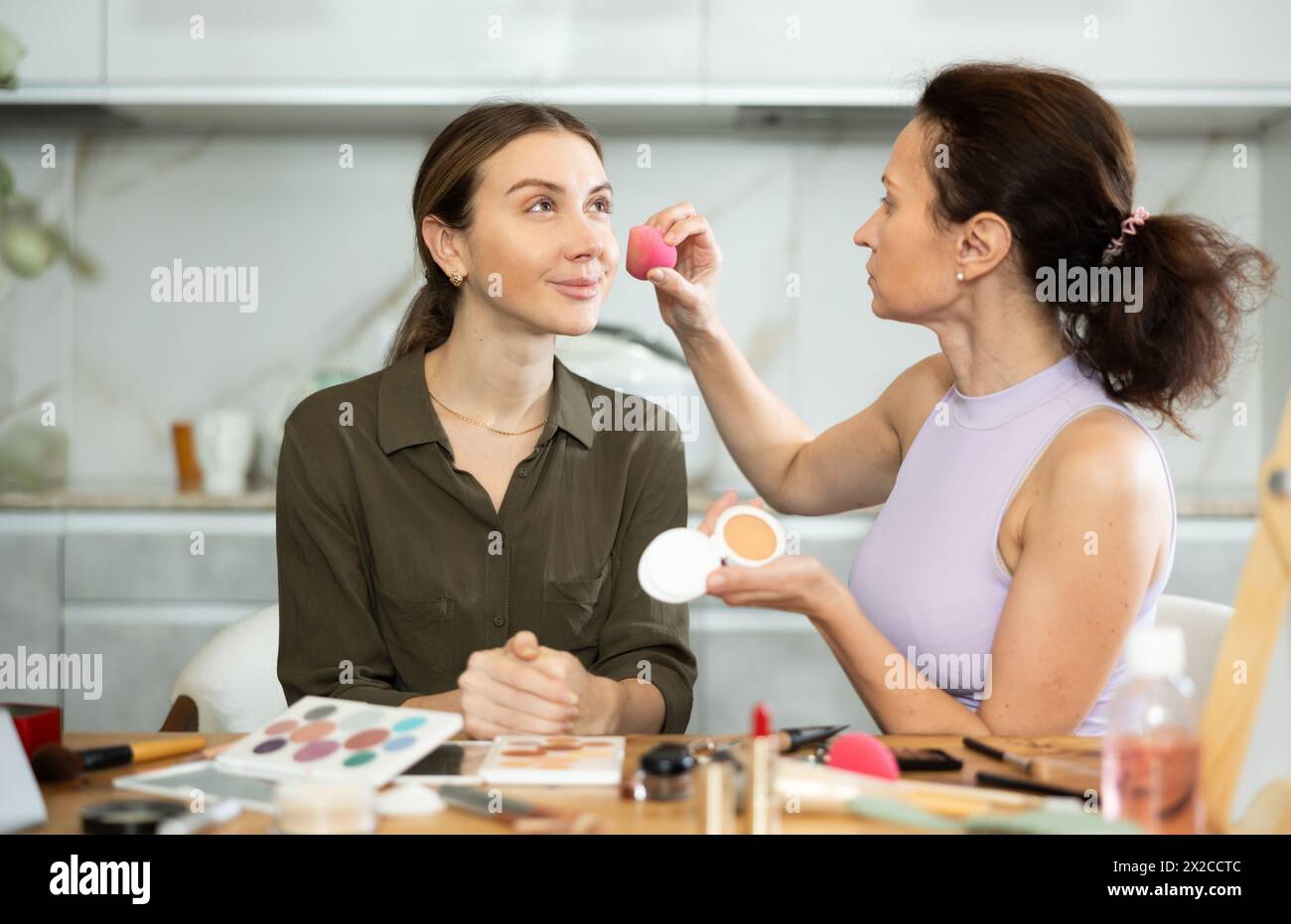 Adult woman doing makeup to young woman Stock Photo - Alamy