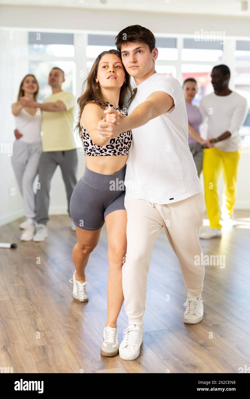 Expressive guy and girl practicing tango during group dance class Stock ...