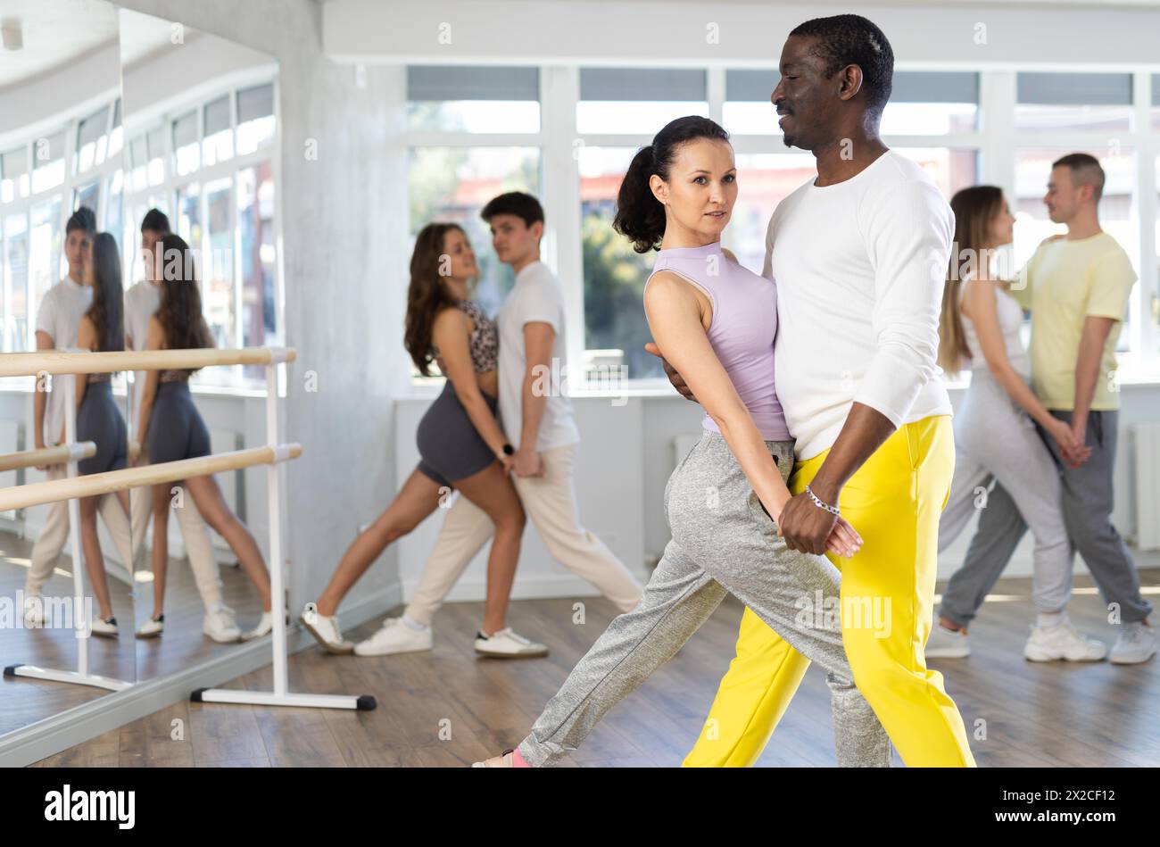 Beautiful young woman at dance salon with her african american partner ...