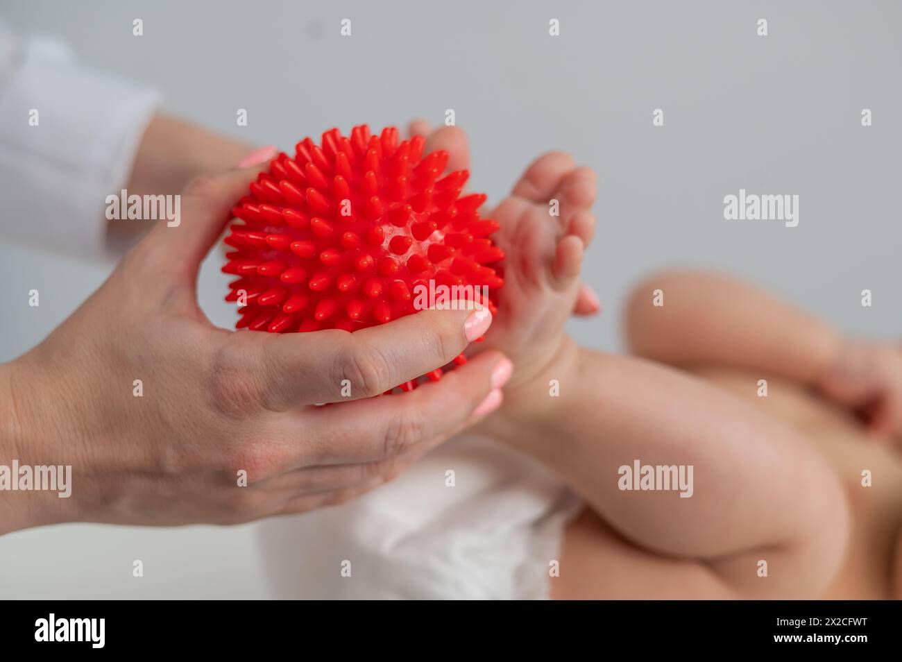 A doctor massages a baby's foot using a spiked ball Stock Photo - Alamy