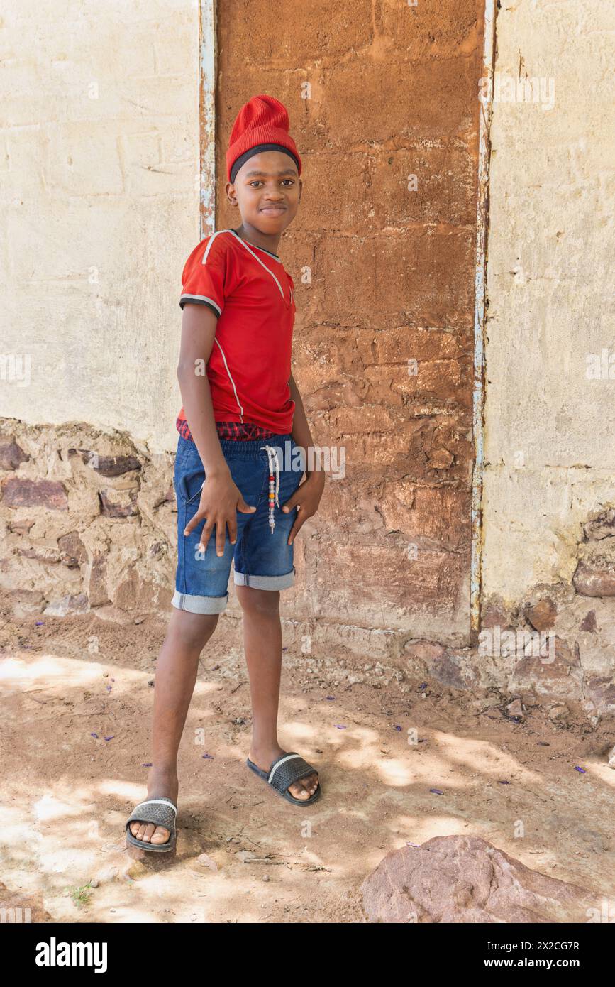 smiling african villager child playing outdoors in front of the house ...
