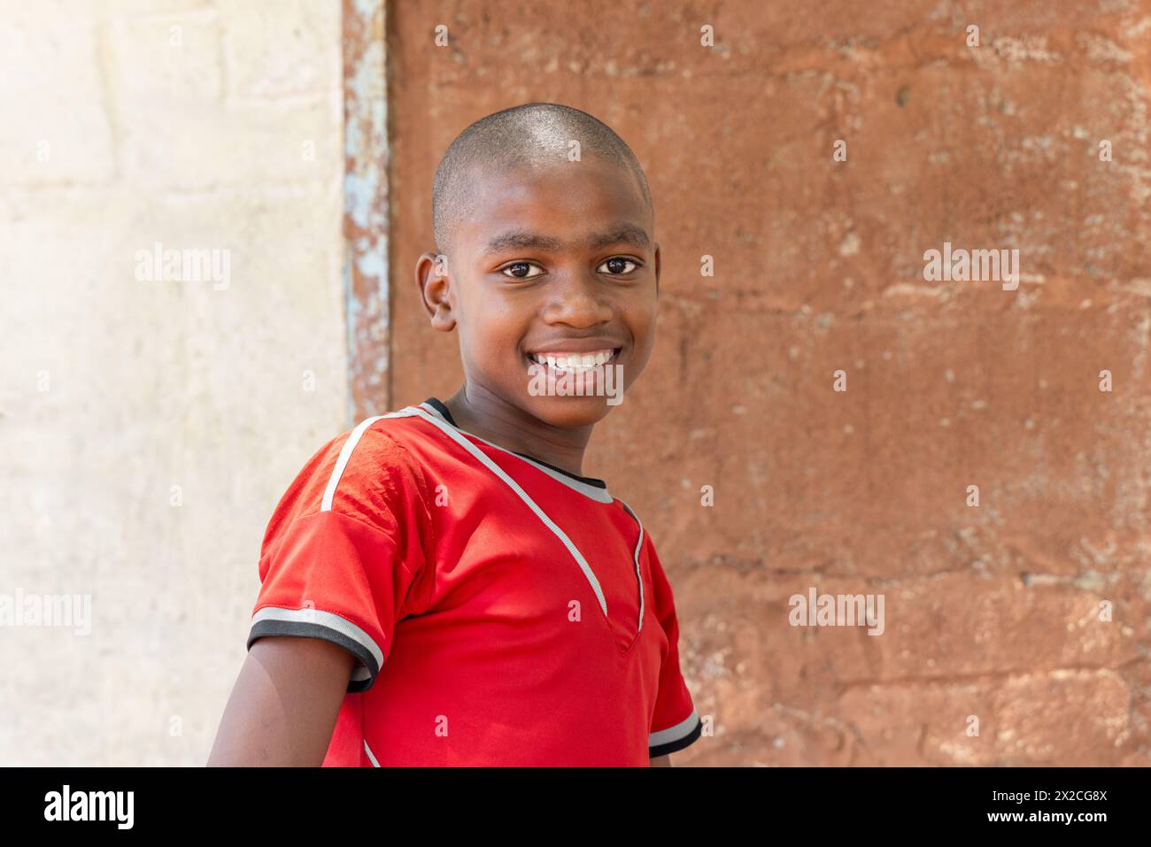 smiling african villager child playing outdoors in front of the house ...