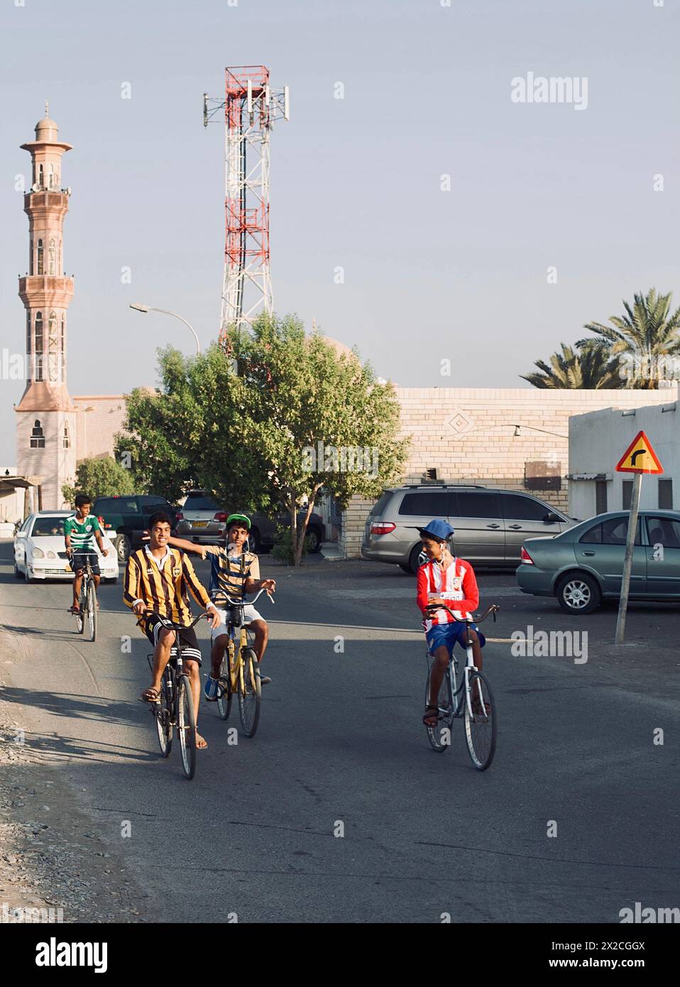 Happy teenagers, arabic boys riding bicycles and chatting in Oman ...