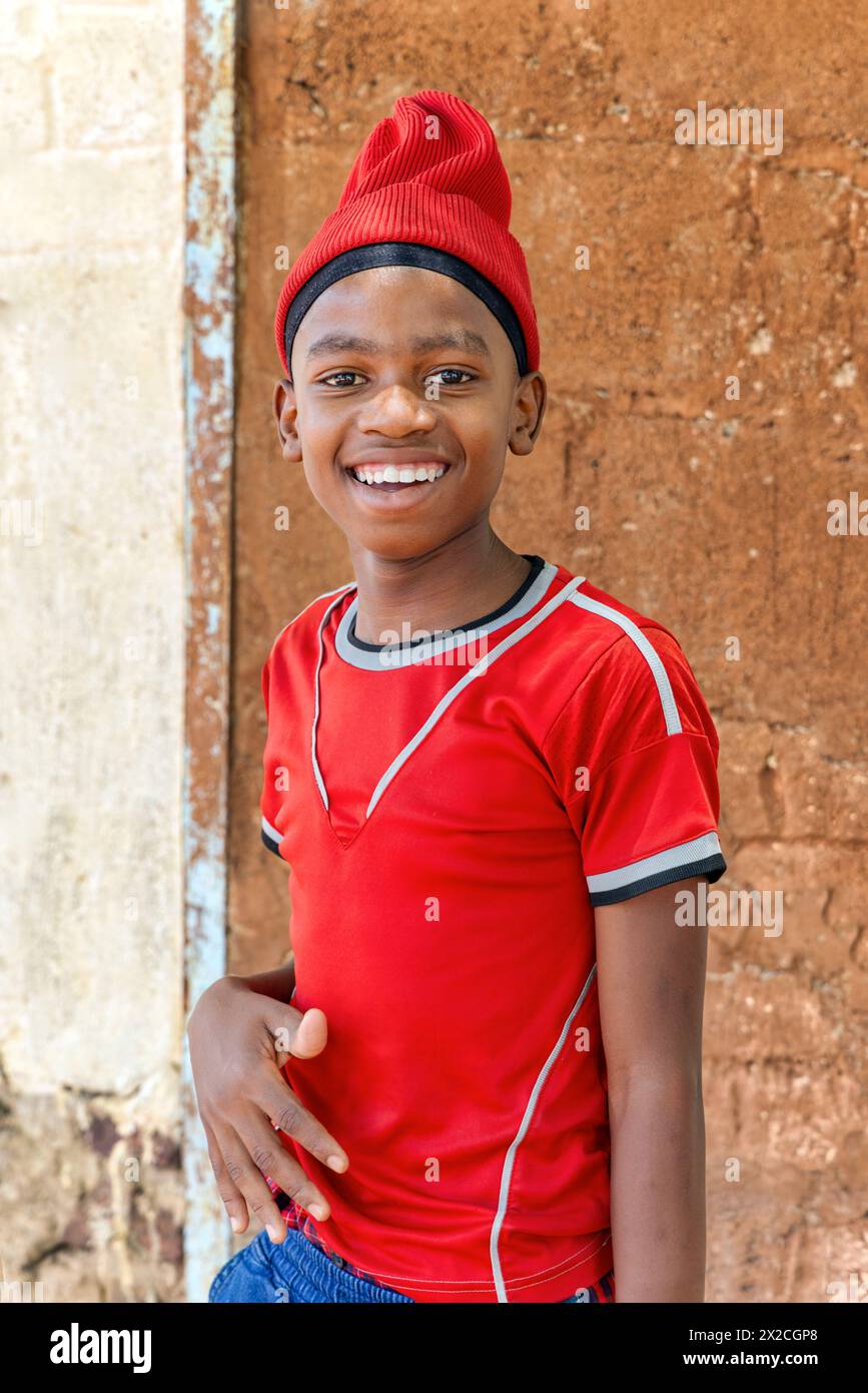 smiling african villager child with a beanie playing outdoors in front ...