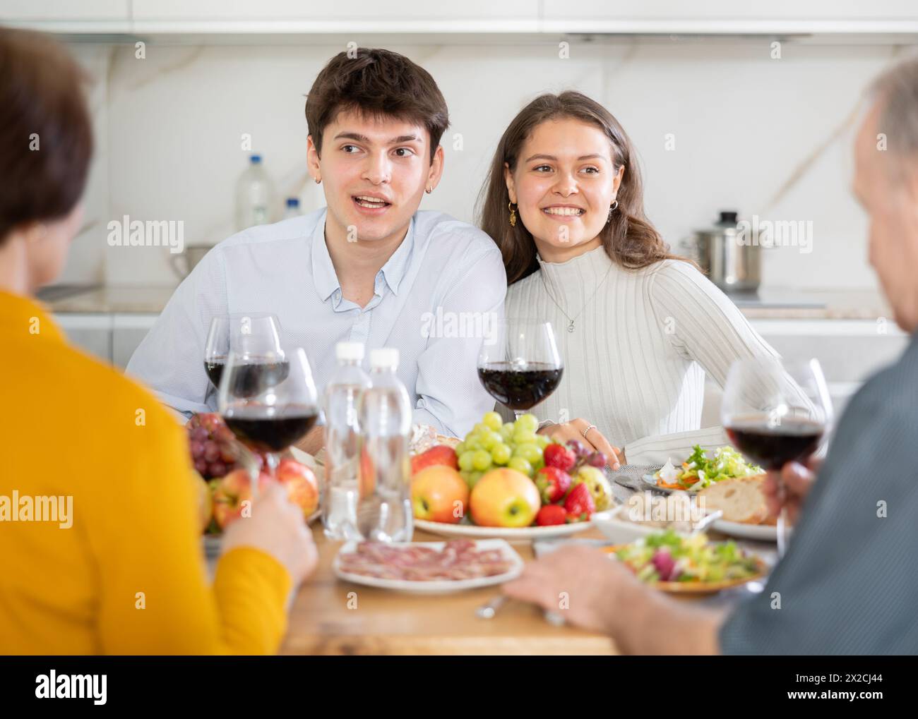 Smiling guy with wife visiting parents. Young couple sitting with ...