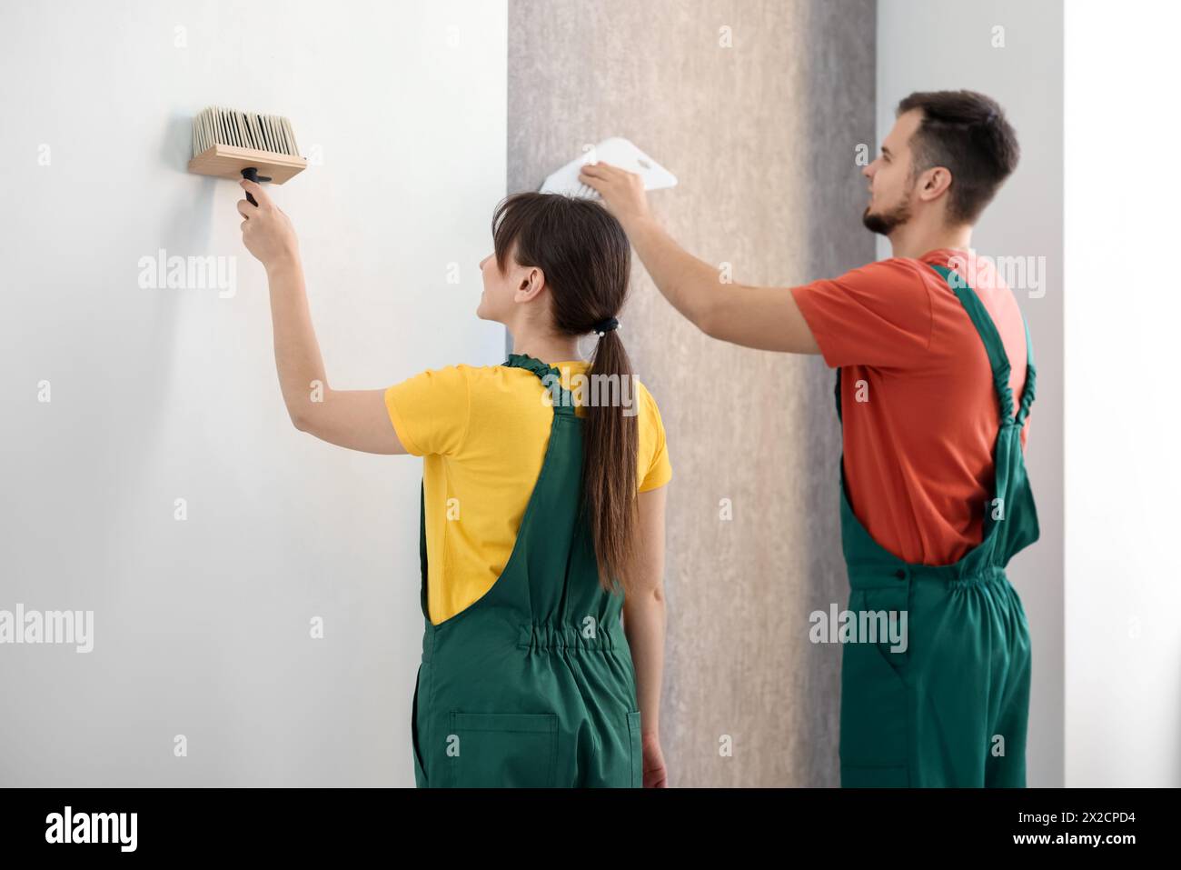 Workers hanging stylish gray wallpaper in room Stock Photo - Alamy