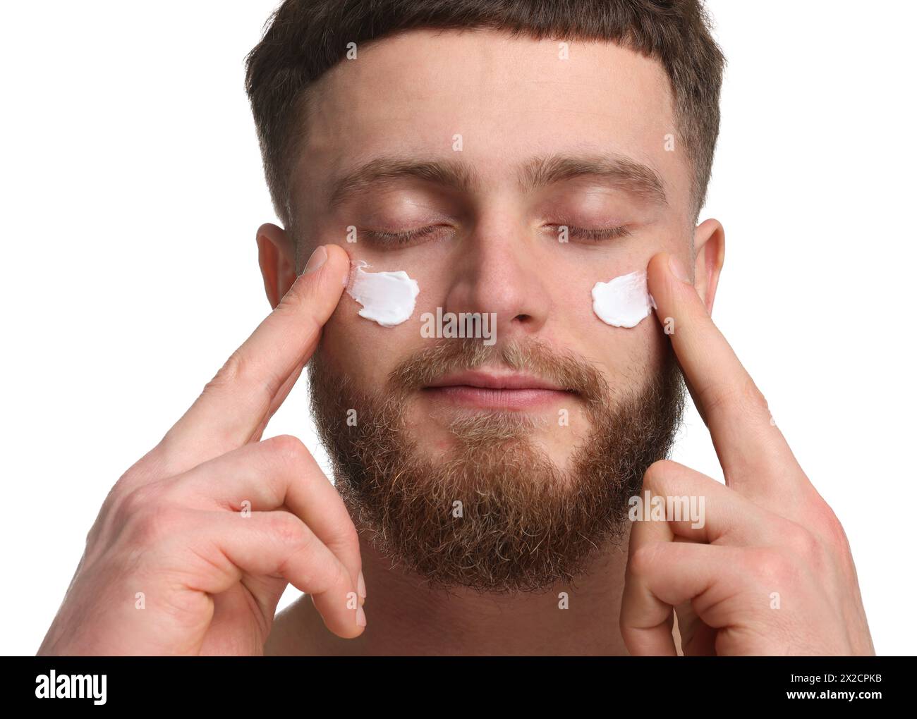 Handsome man applying moisturizing cream onto his face on white ...