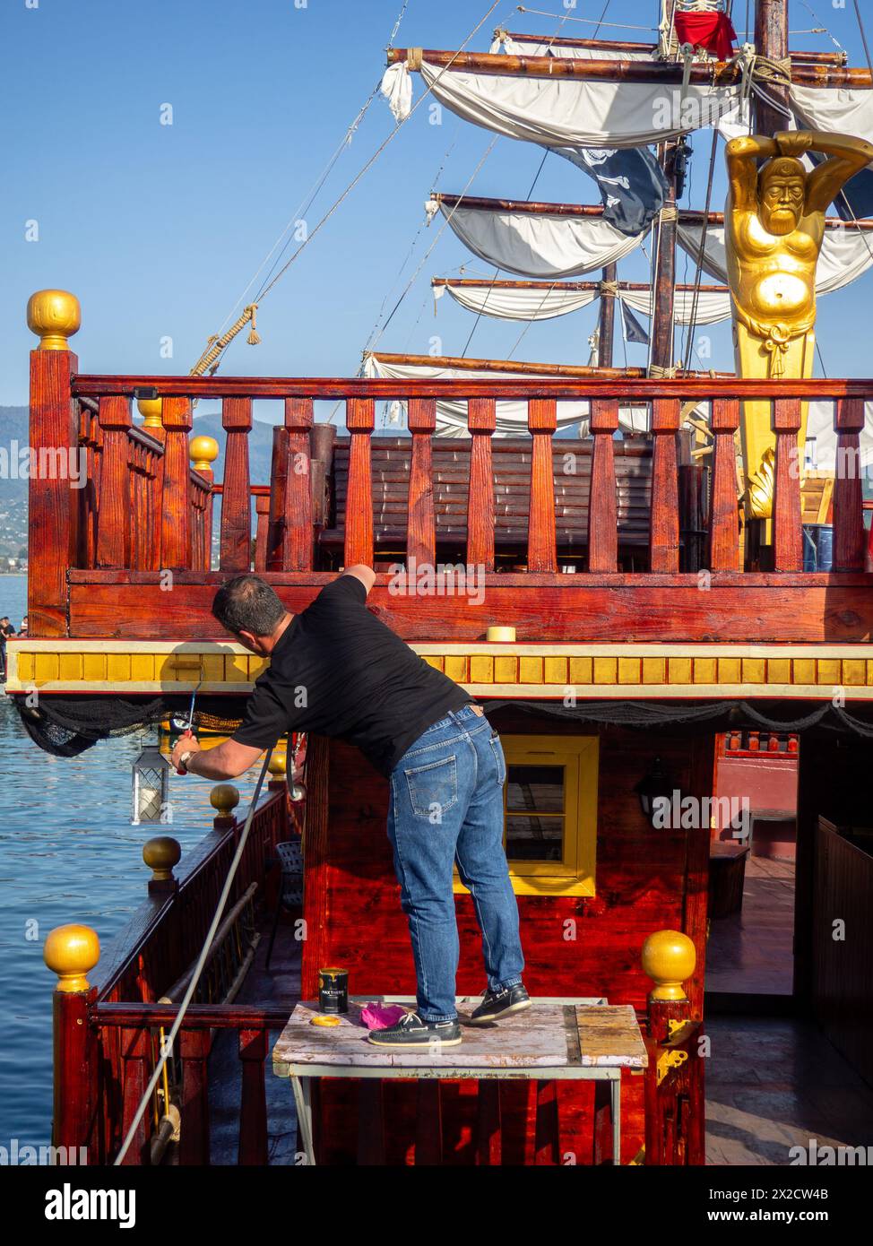 A pleasure boat made to look like a pirate ship. A worker works on the ...