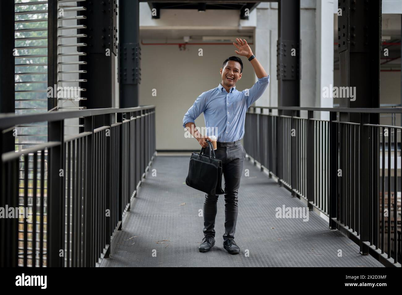 A cheerful, friendly Asian millennial businessman waving to greet his ...