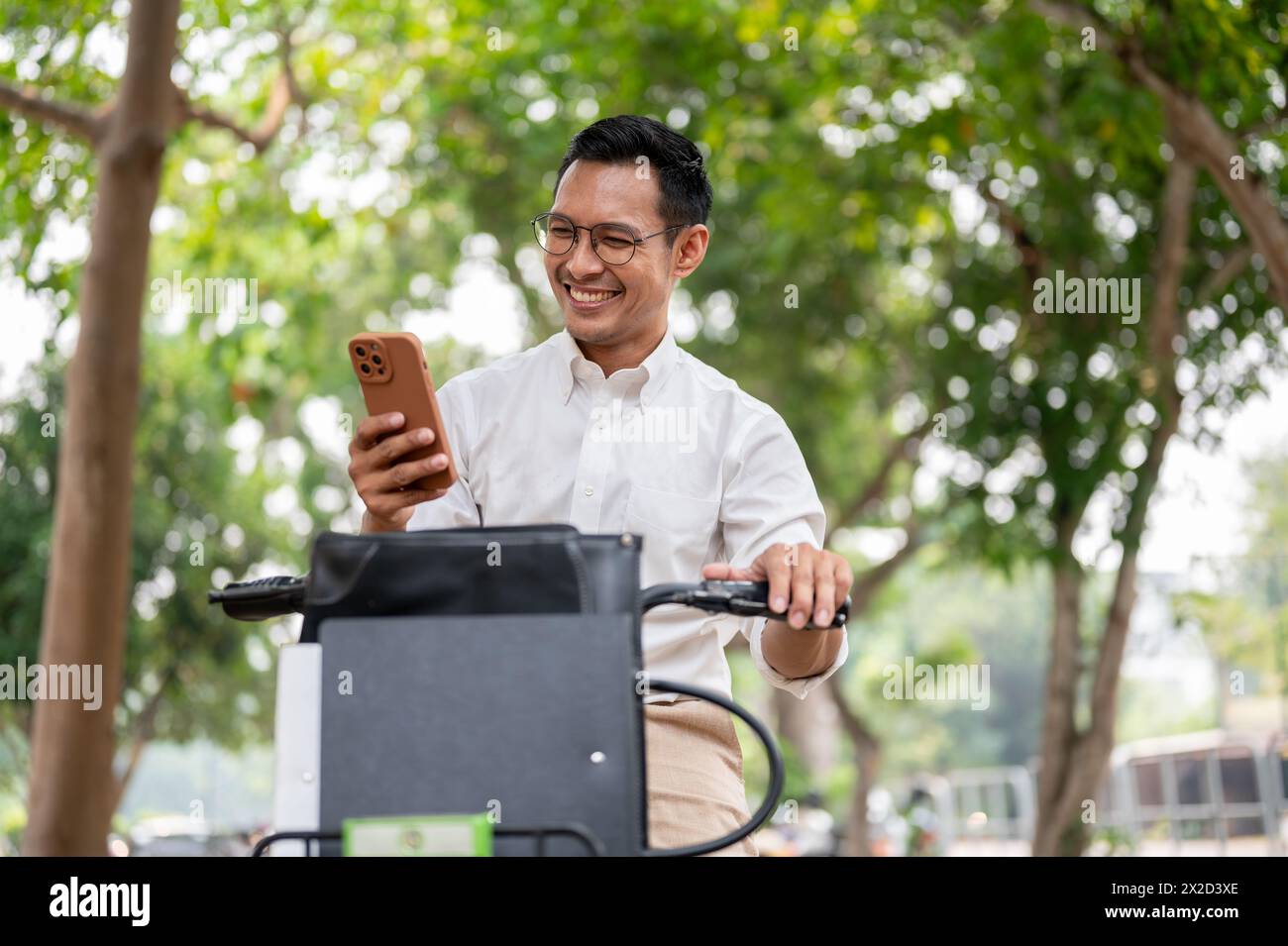 A happy, carefree Asian millennial businessman is checking messages on ...