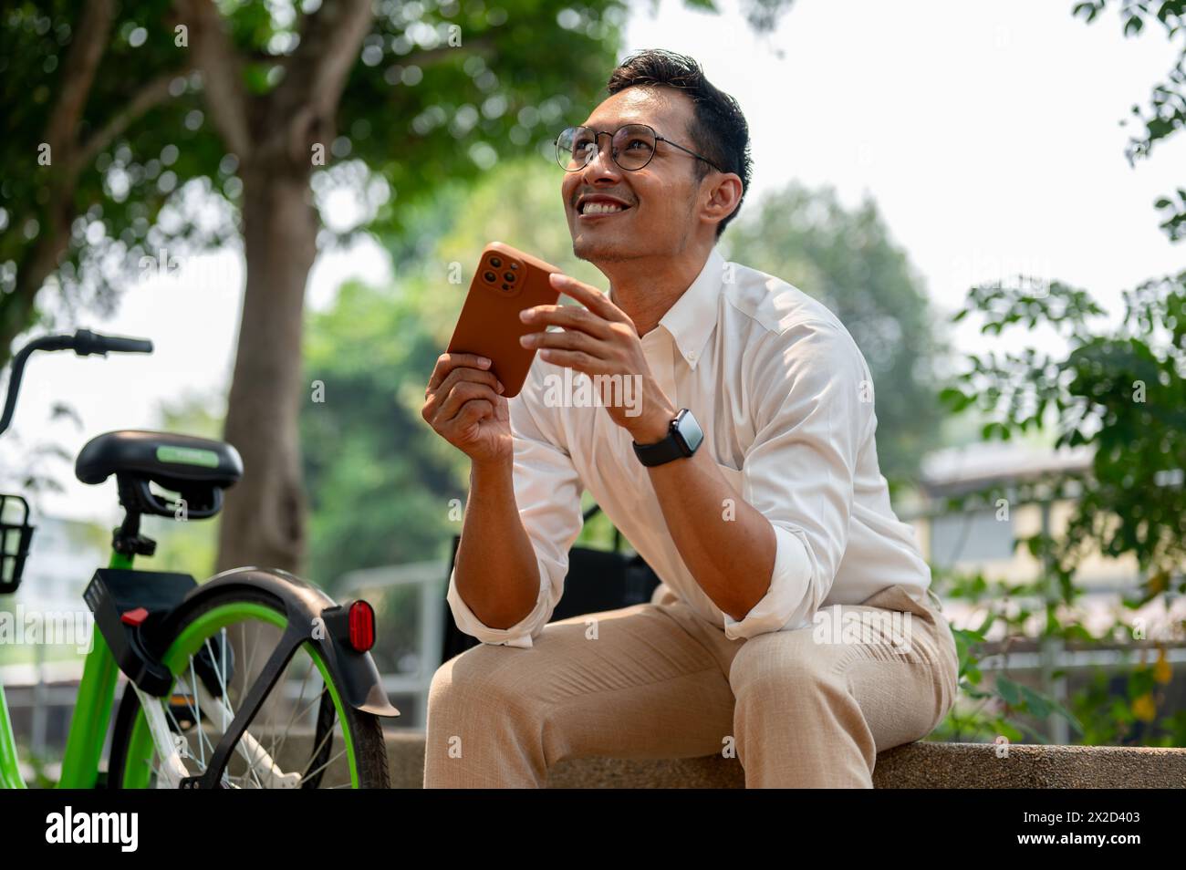 Smiling millennial sits on park hi-res stock photography and images - Alamy