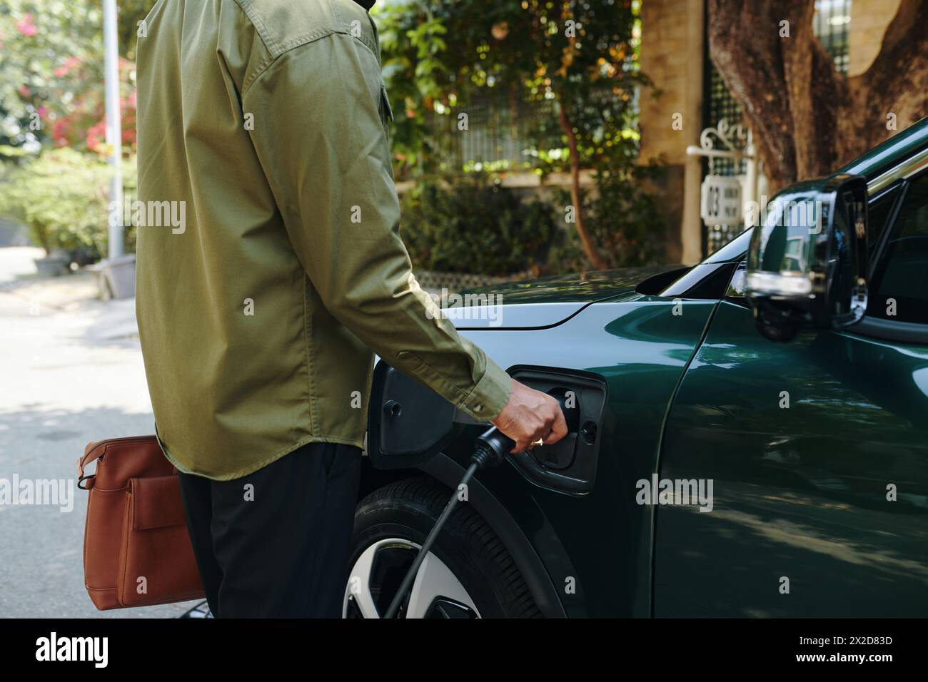 Cropped image of electric car owner inserting charging plug Stock Photo ...