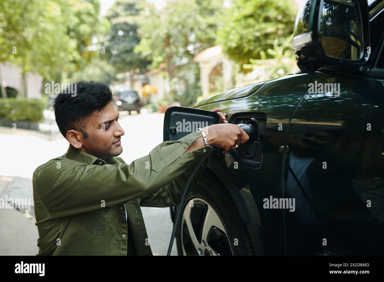Electric car driver charging his vehicle before ride Stock Photo - Alamy