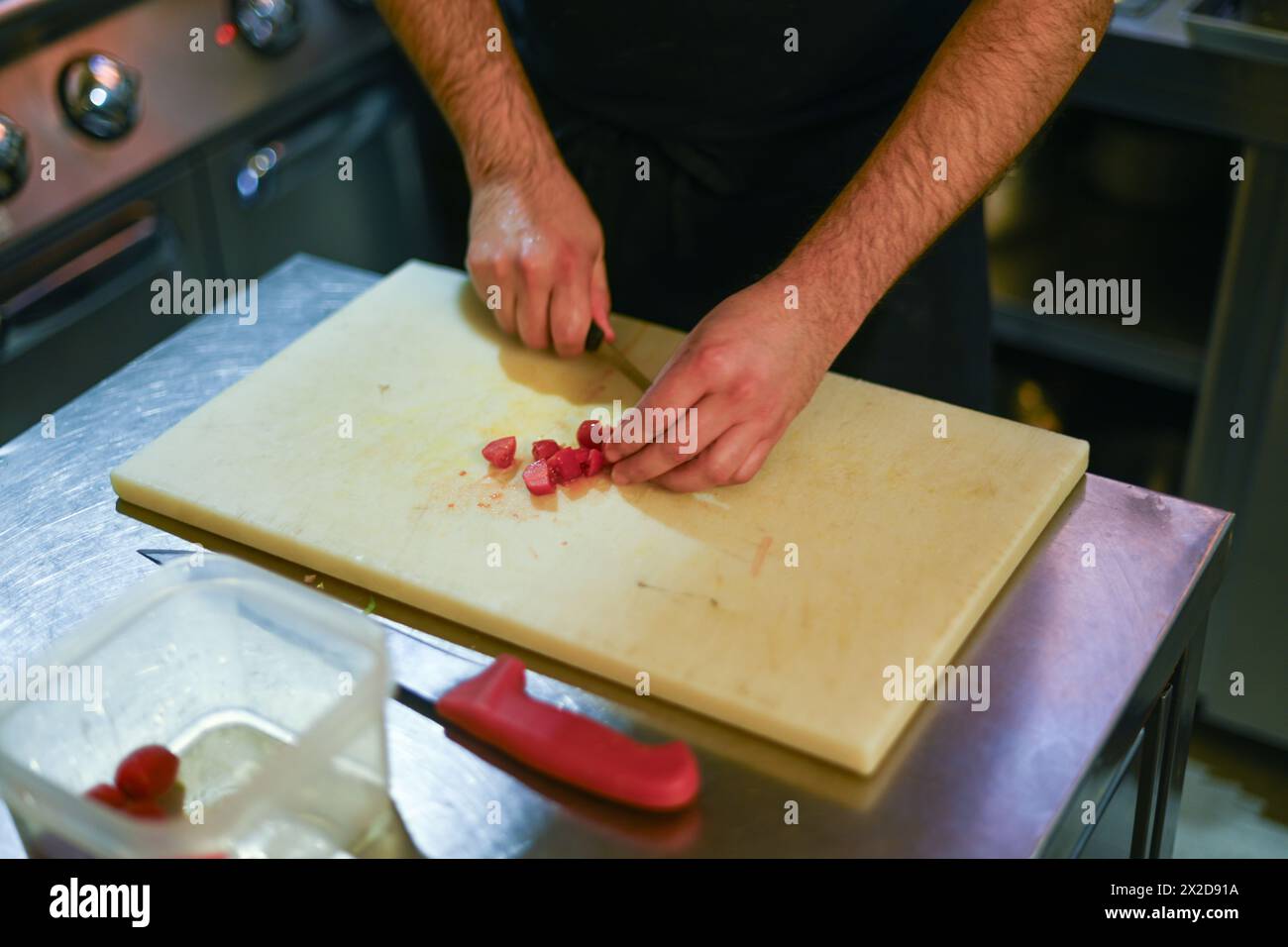 A man is cutting up some cherry tomato on a cutting board. Concept of ...