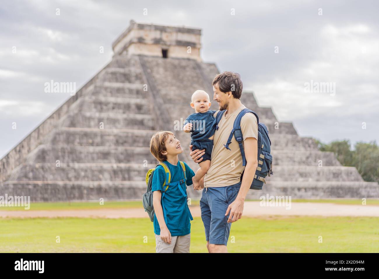 Father and two sons tourists observing the old pyramid and temple of ...