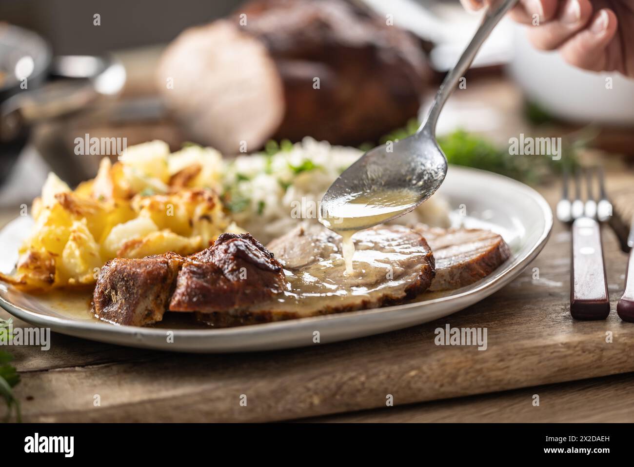 A close-up view of a spoon with sauce that pours over the meat, roasted ...
