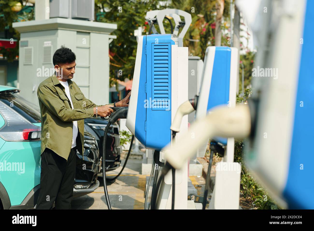 Ev driver taking plug at charging point Stock Photo - Alamy