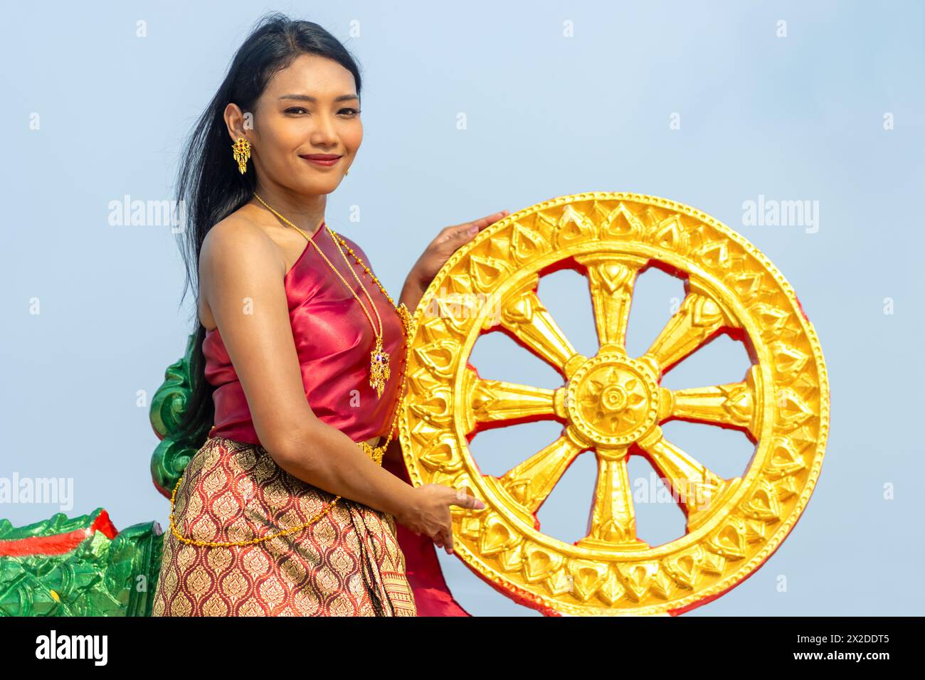 A young woman in a Thai dancer costume holds a dharma wheel, a symbol ...