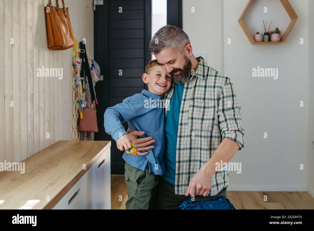 Father helping son get ready for kindergarten, preschool. Putting coat ...