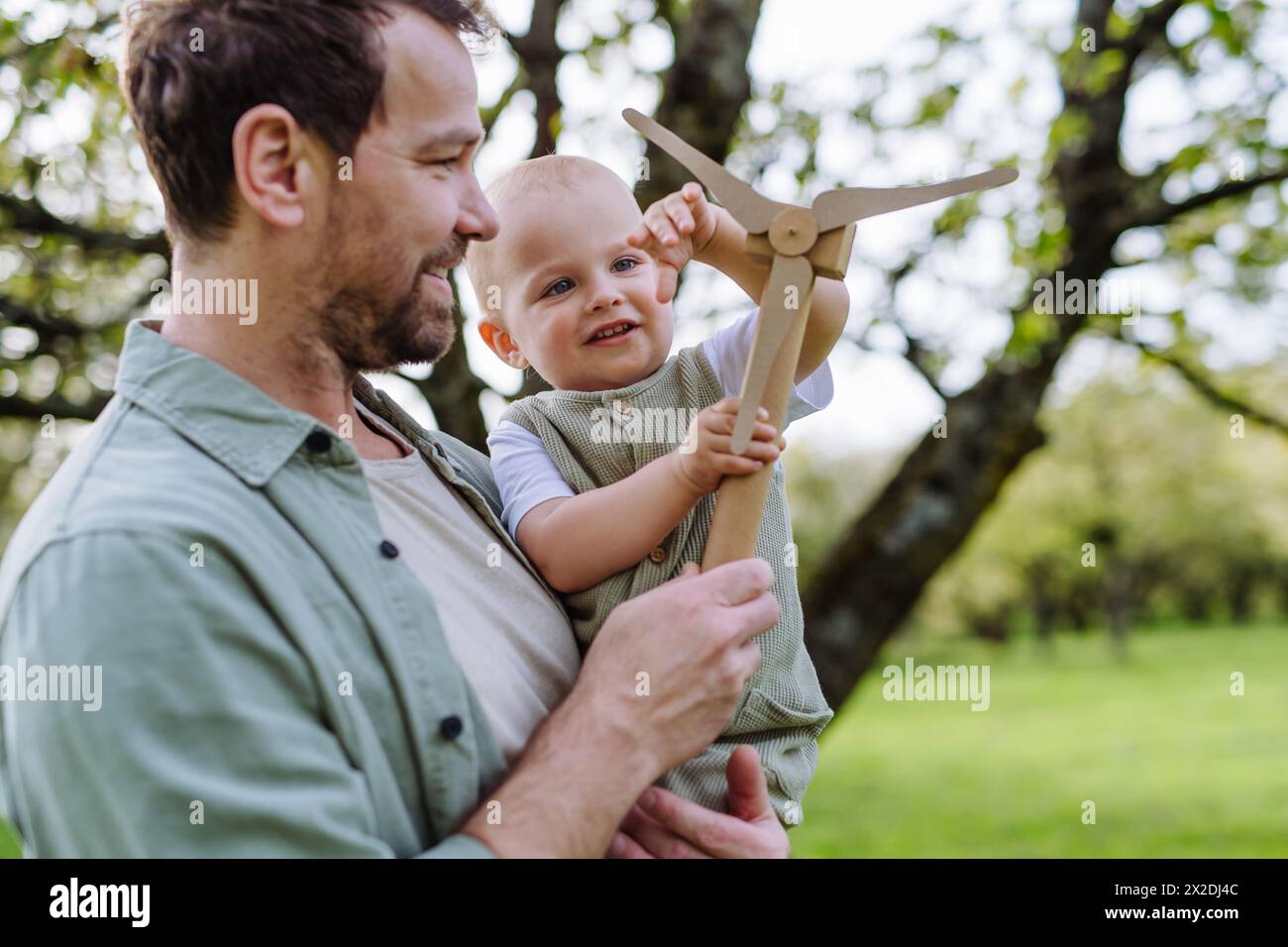 Baby and father holding wind turbine model, outdoors in park. Concept ...