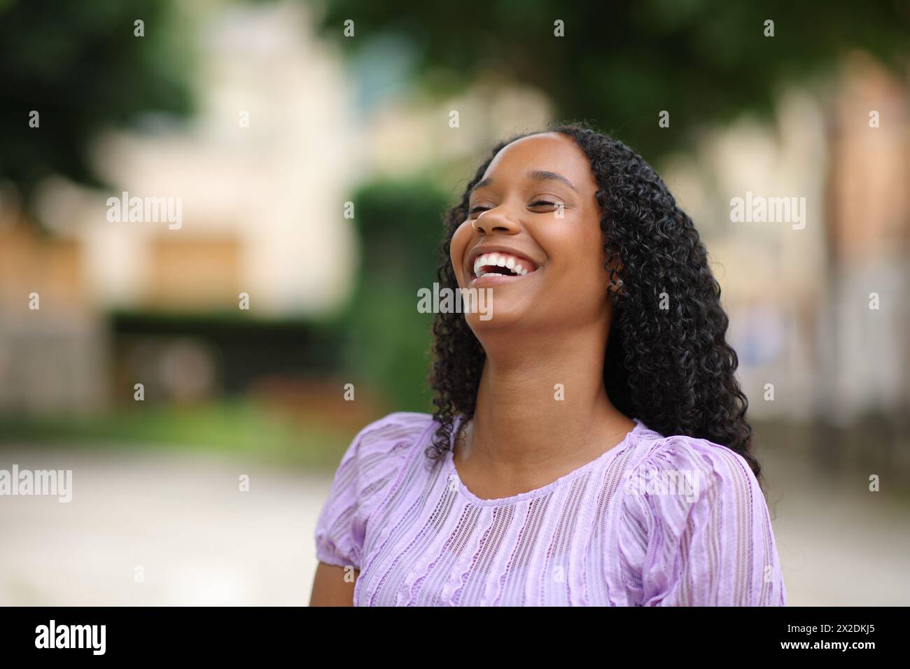 Happy black woman laughing loud alone in the street Stock Photo - Alamy