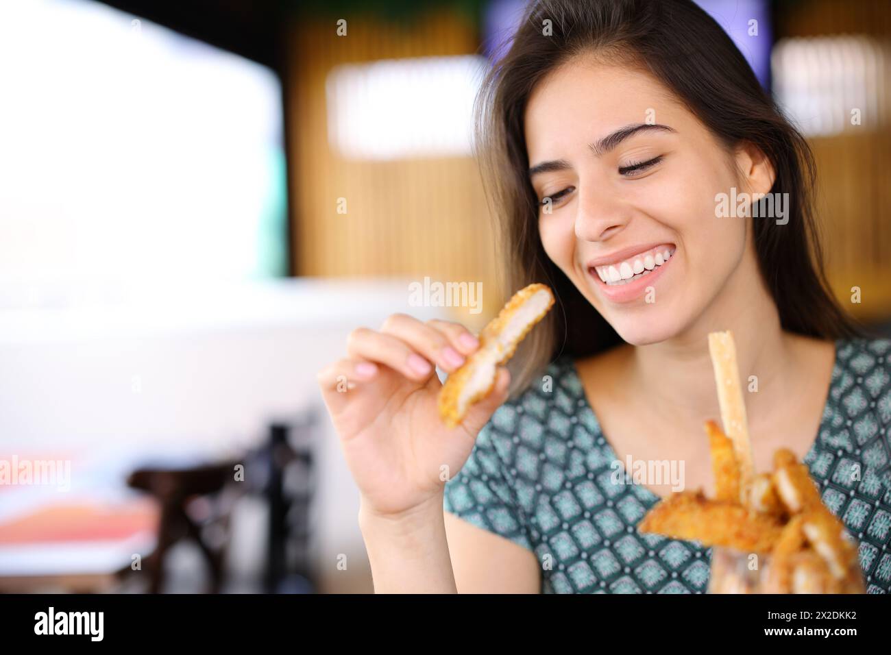 Happy woman eating chicken fingers alone in a restaurant interior Stock ...
