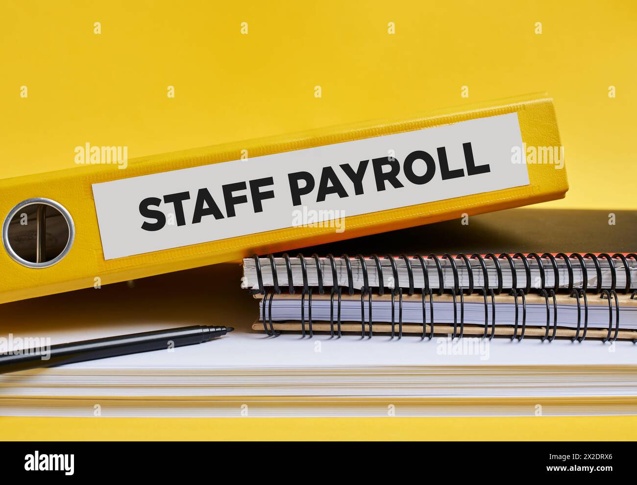 The word staff payroll written on the label of a yellow binder on the ...