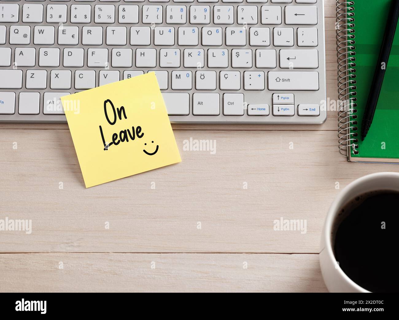 On leave message handwritten on a sticky note paper on the office desk ...