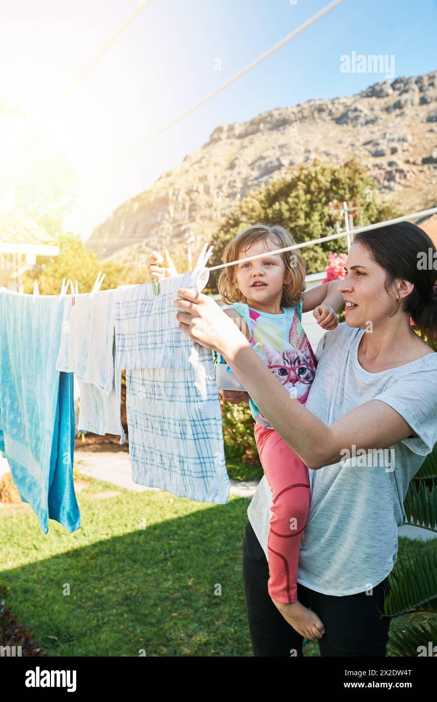 Backyard, mom and child hanging laundry together with help, teaching ...
