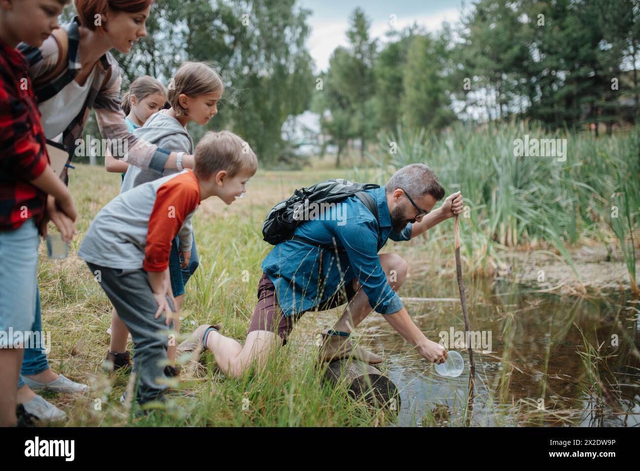 Teacher showing lake water to school children, during field teaching ...