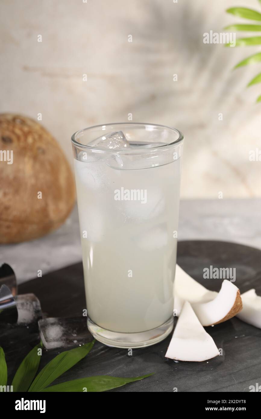 Glass of coconut water, ice cubes and nuts on table Stock Photo - Alamy