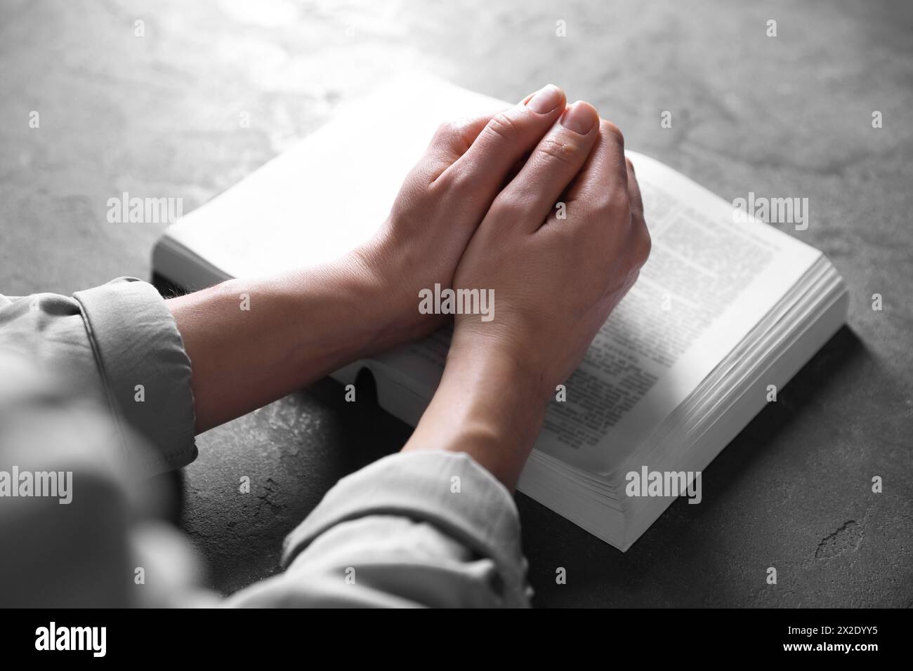 Religion. Christian woman praying over Bible at gray table, closeup ...