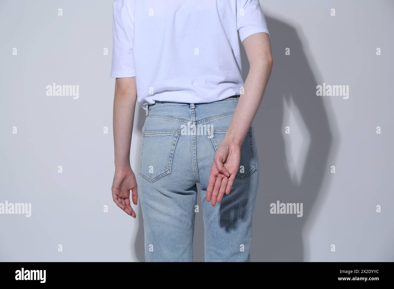 Woman showing open palm behind her back on light background, back view ...