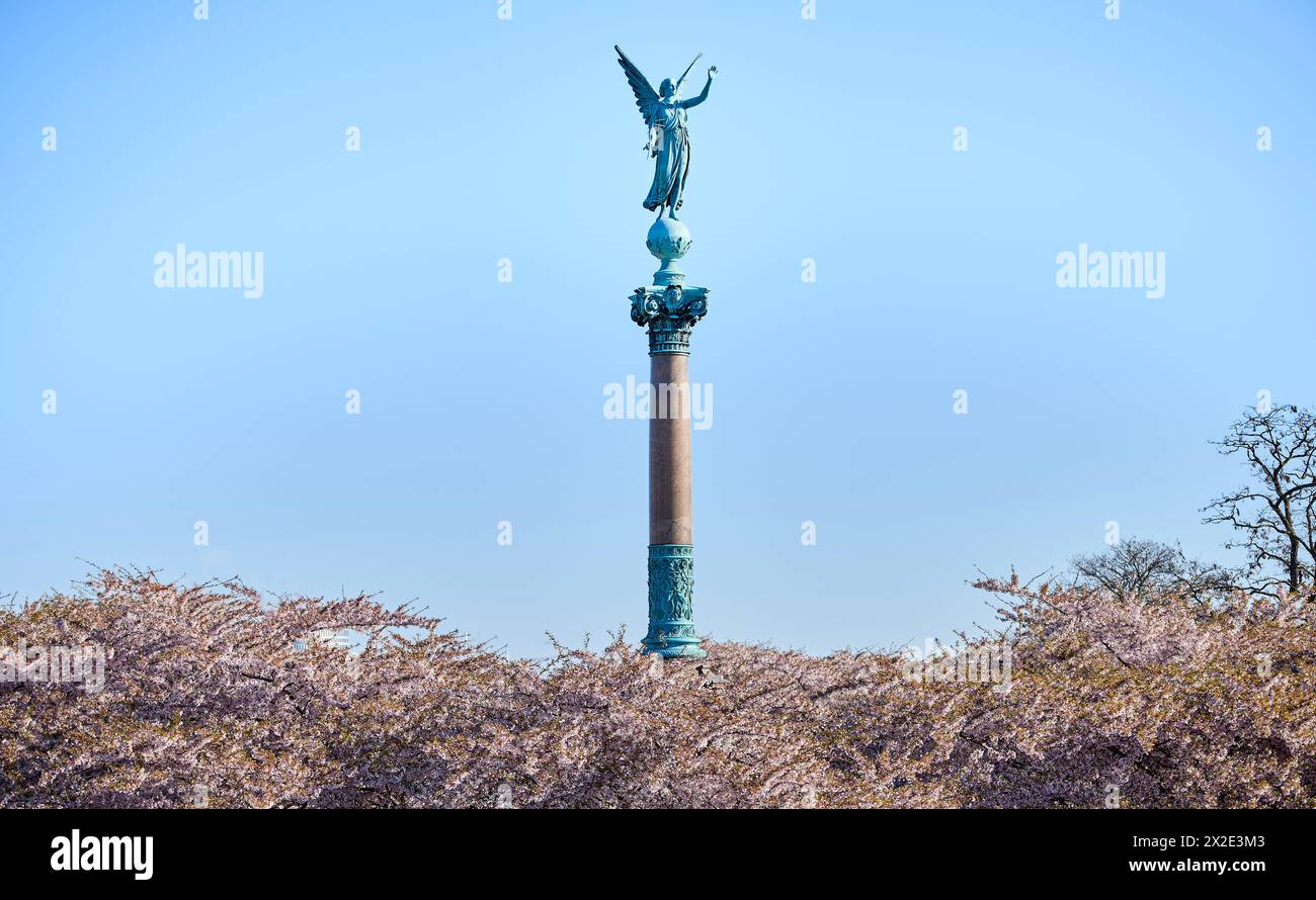 Angelic statue for the fallen in war saluting high on blooming pink ...