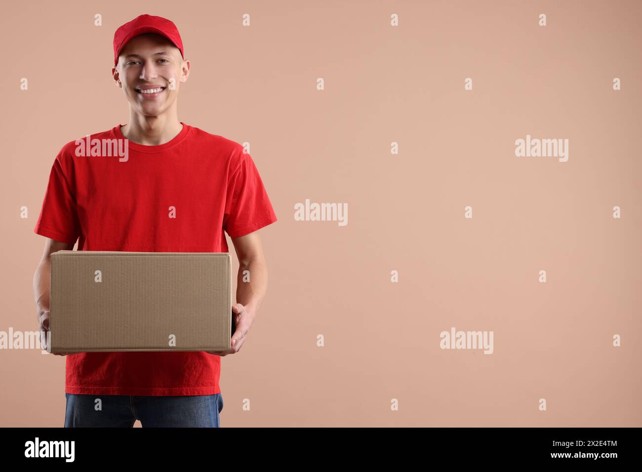 Happy courier with parcel on beige background. Space for text Stock ...