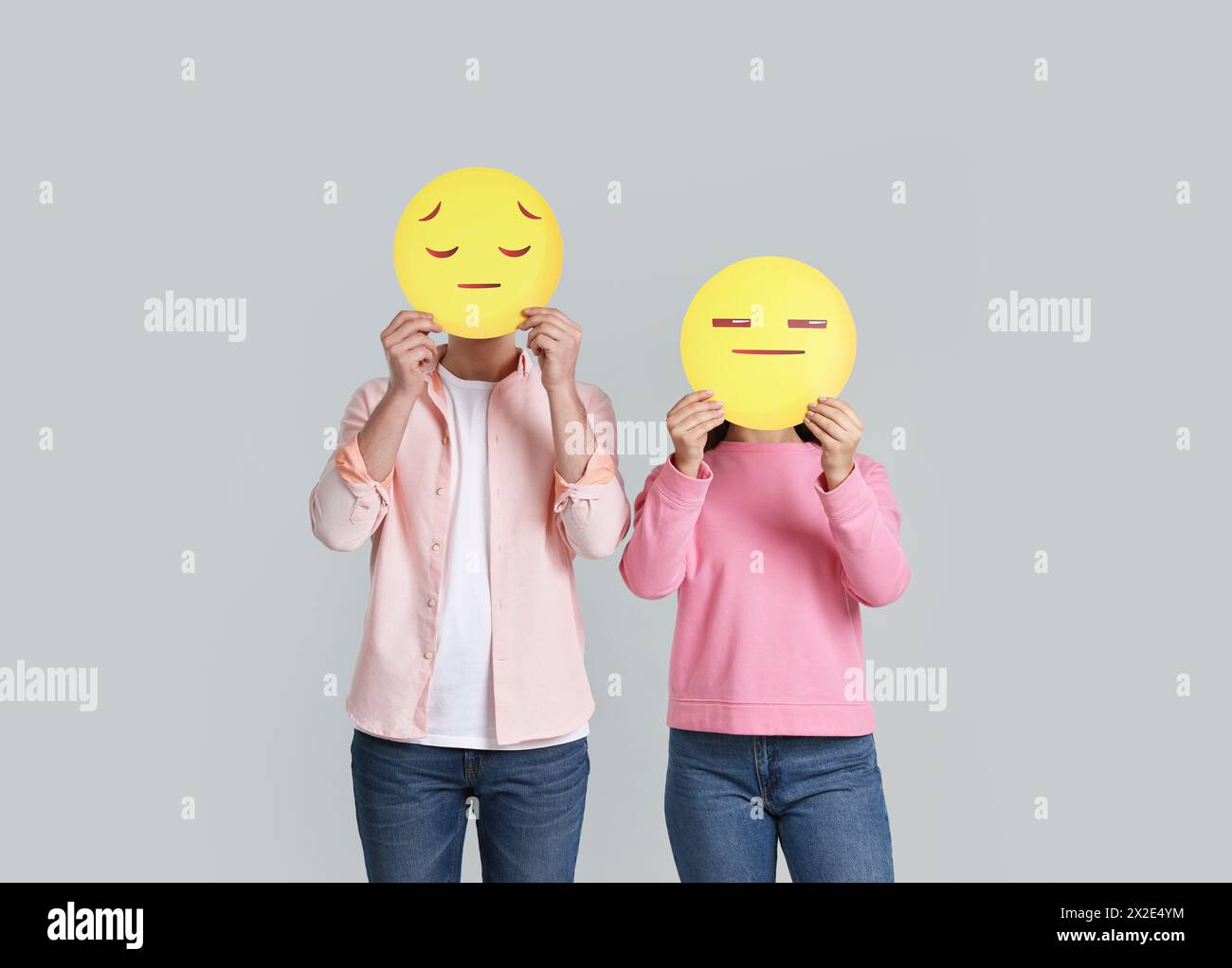 People covering faces with sad emoticons on grey background Stock Photo ...