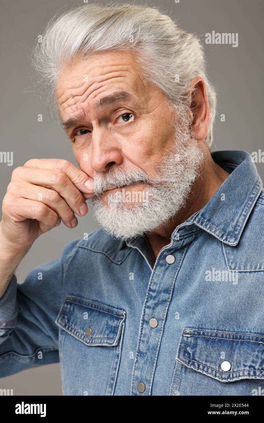 Senior man touching mustache on grey background Stock Photo - Alamy