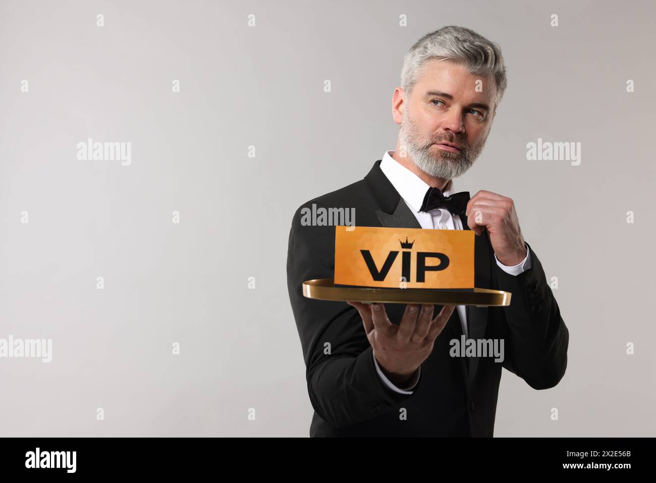 Handsome man holding tray with VIP sign on light grey background. Space ...