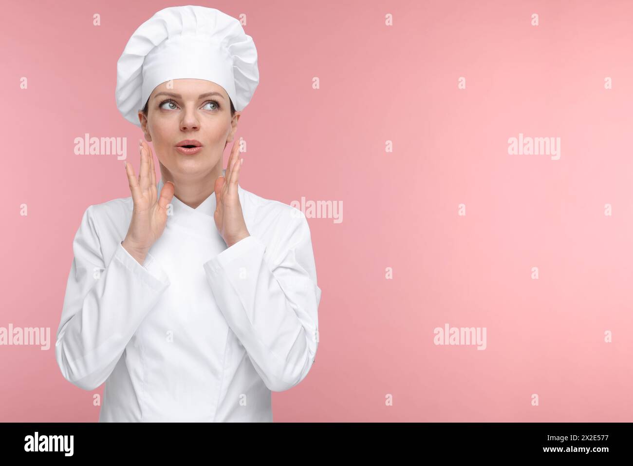 Confused woman chef in uniform on pink background, space for text Stock ...