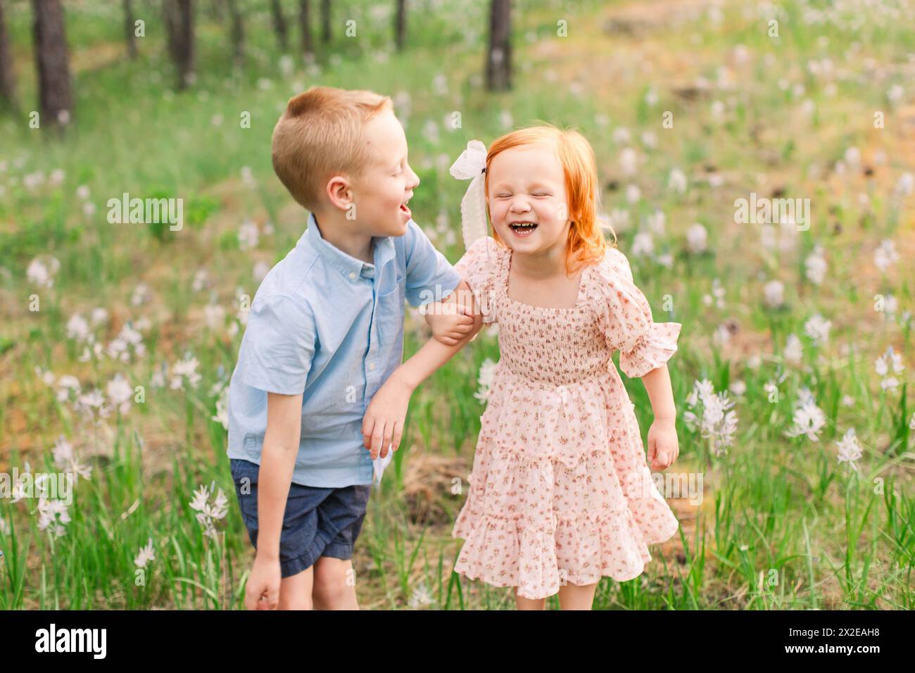 Joyful siblings laughing together in a wildflower field Stock Photo - Alamy