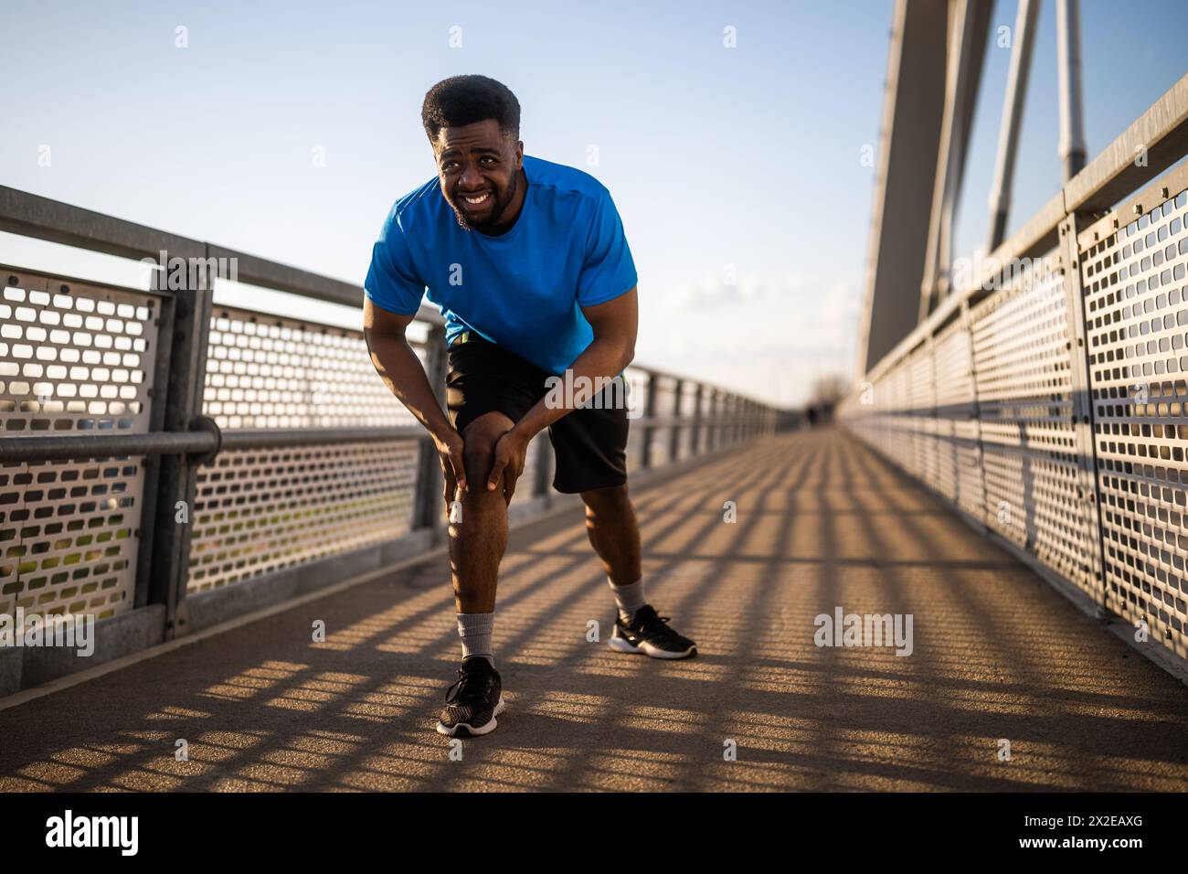 Young african-american man is injured while jogging. He has pain in ...