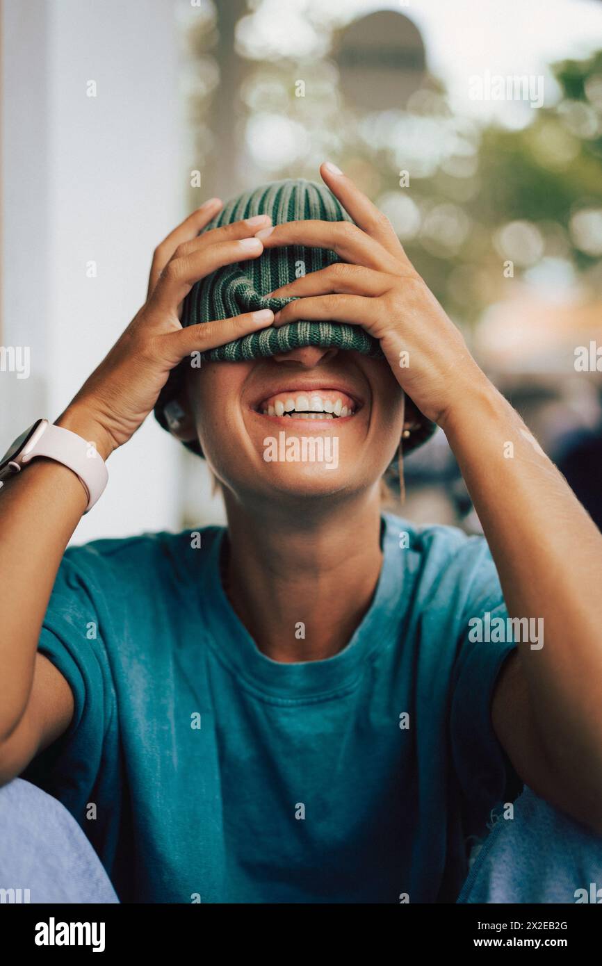 Happy laughing woman pulling her cap over her eyes. Fool Stock Photo ...
