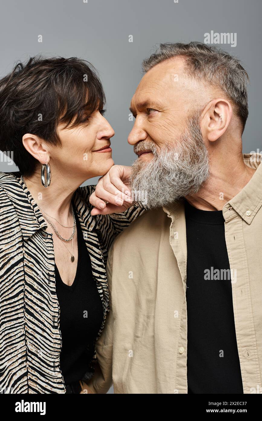 A middle-aged man and woman stand side by side in stylish attire ...