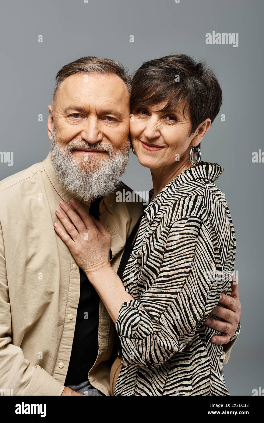 A middle-aged man and woman, stylishly dressed, share a warm embrace in a studio setting Stock ...