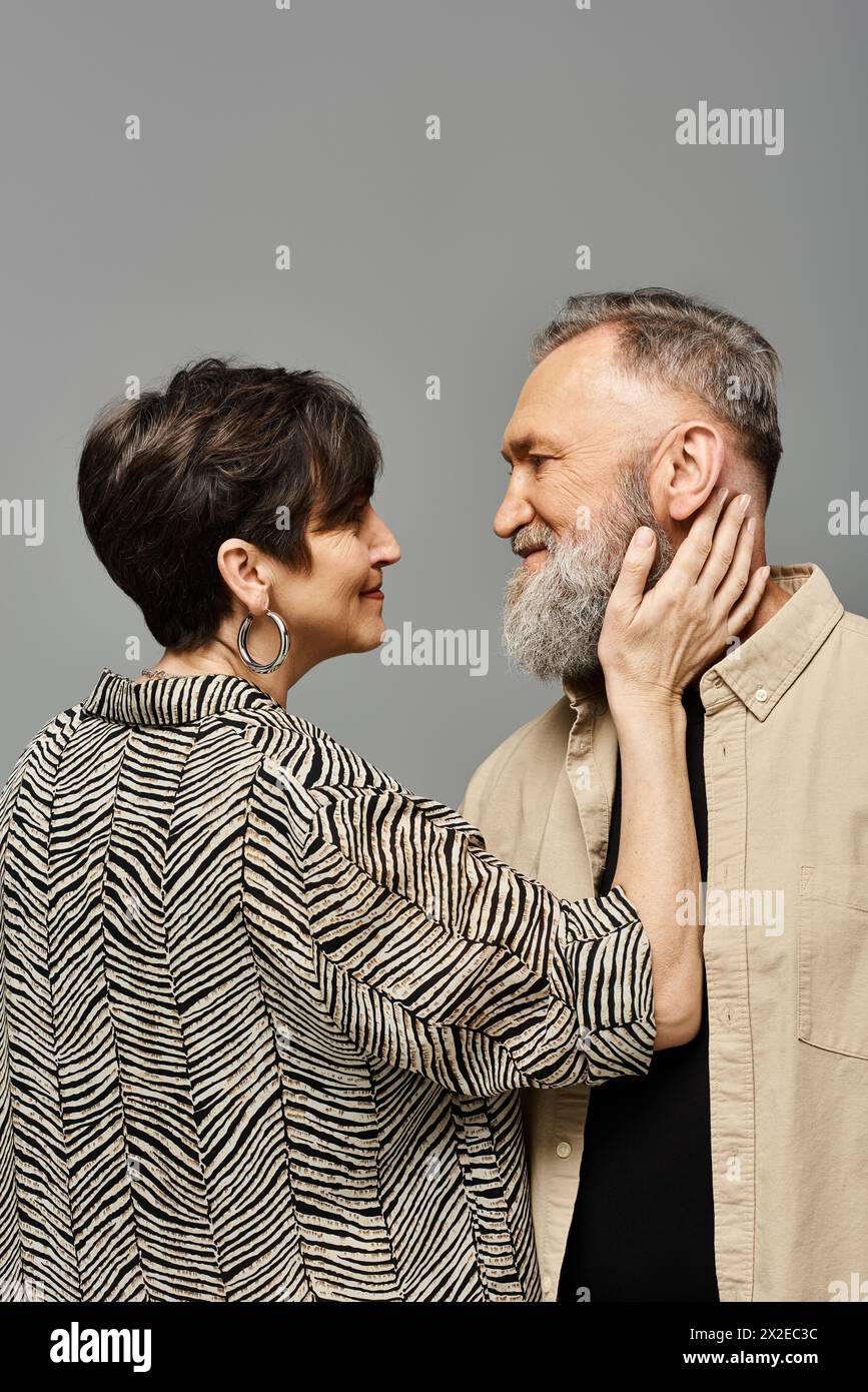 A middle-aged man and woman in stylish attire stand gracefully side by ...