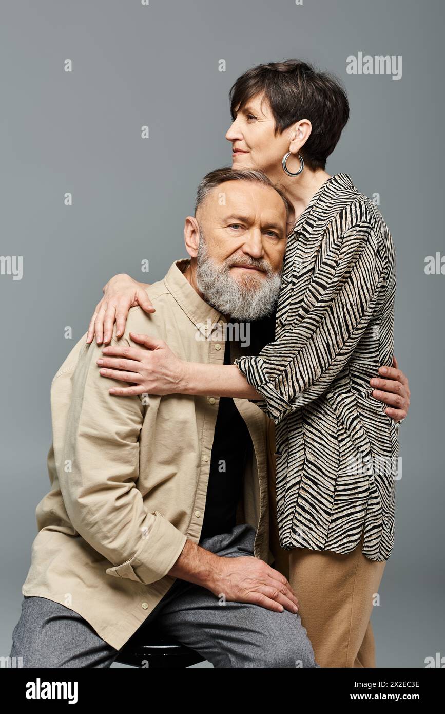 A middle-aged man and woman, clad in stylish attire, share a tender hug ...