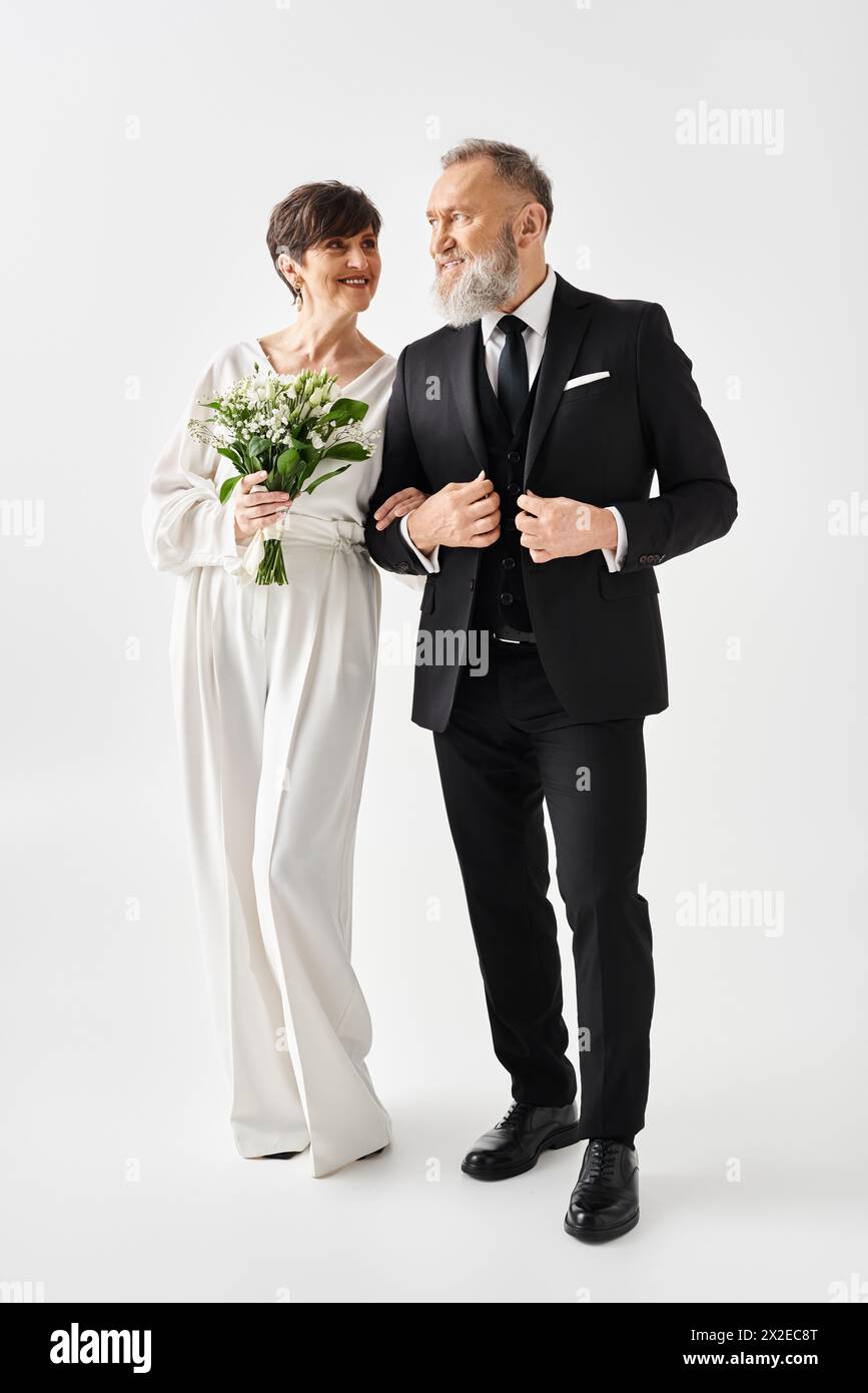 A middle-aged bride and groom in elegant formal wear stand next to each ...